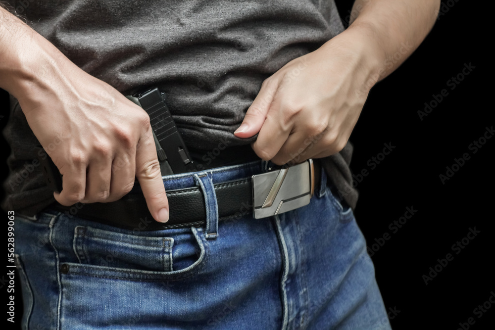 Man drawing a conceal carry pistol from a holster Stock Photo | Adobe Stock
