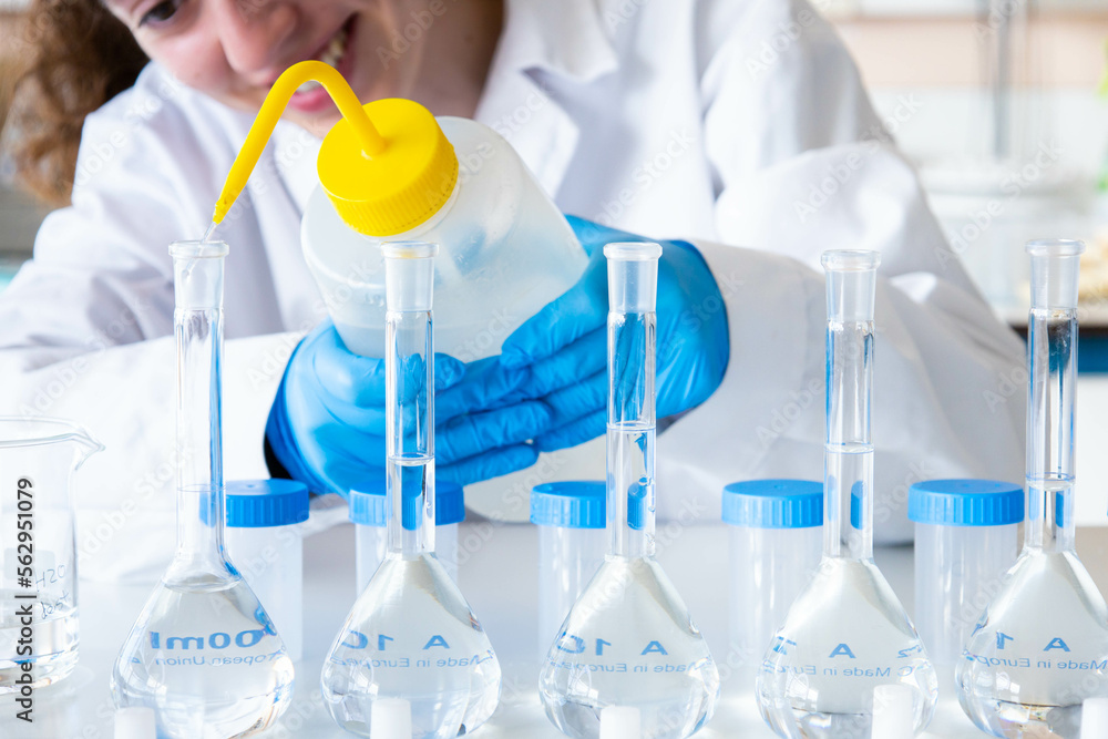 Foto de Close up scientist woman leveling a volumetric flask with a ...