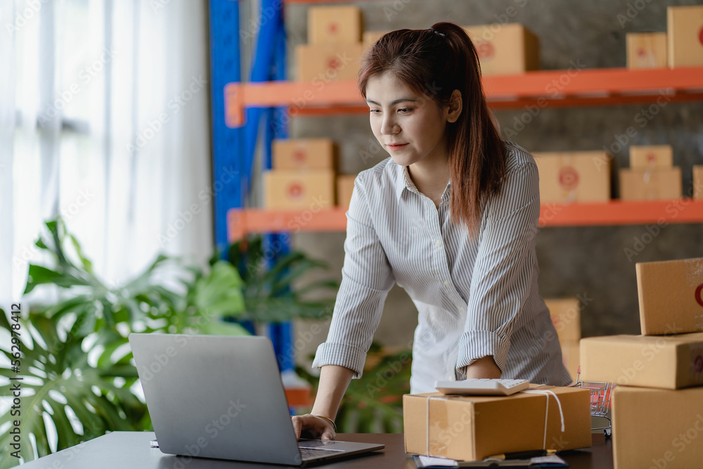 Young Asian woman checking parcels for delivery taking orders with ...