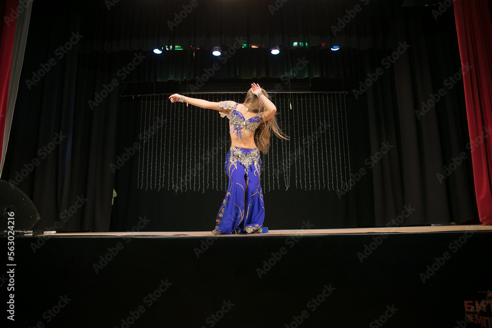 A young dancer with long hair in an oriental costume with a multi ...