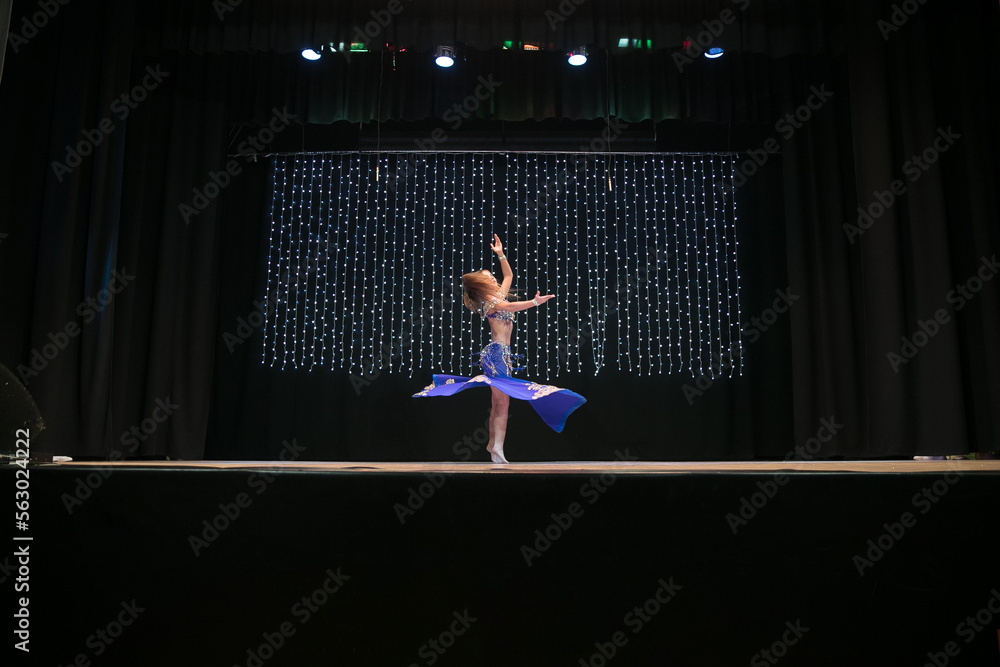 A young dancer with long hair in an oriental costume with a multi ...