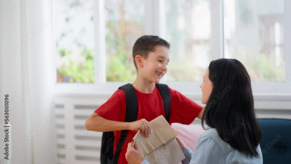 Caring mom giving lunch to her little son before going to school ...