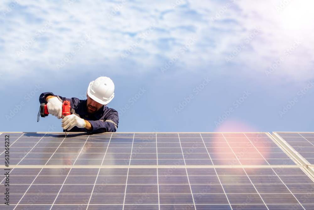 Male technician installing solar panel using electric drill securing solar system installation ...