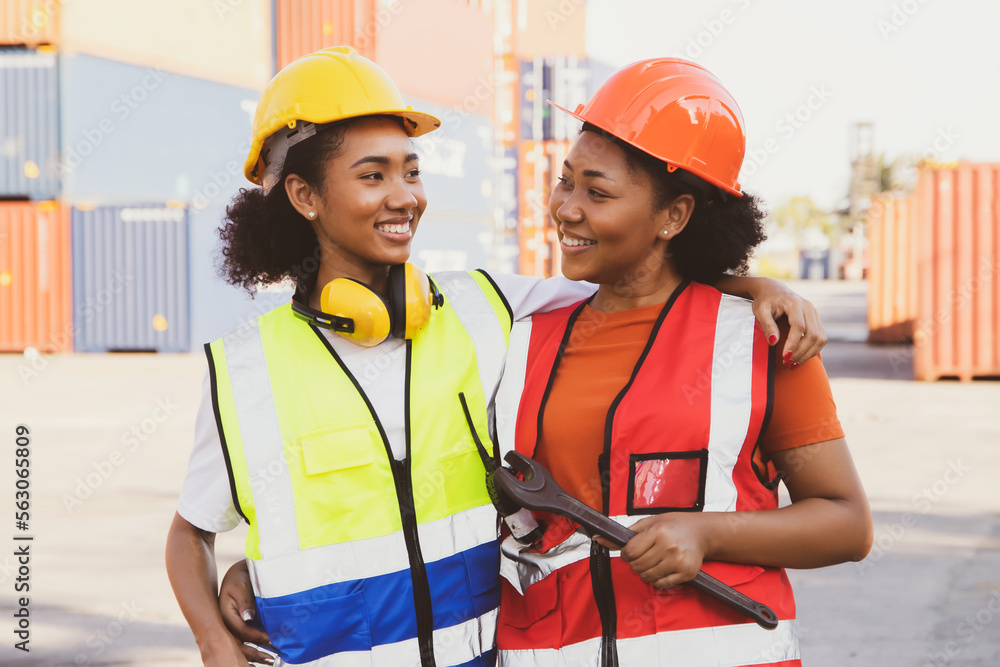 Two african american female workers who match smiling buddy in hard hat ...