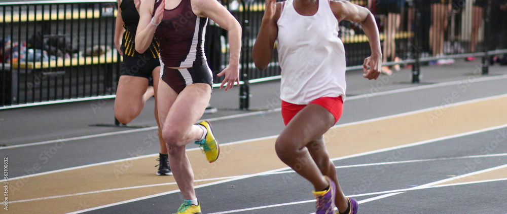 High school girls running to the finish line during an indoor track and ...