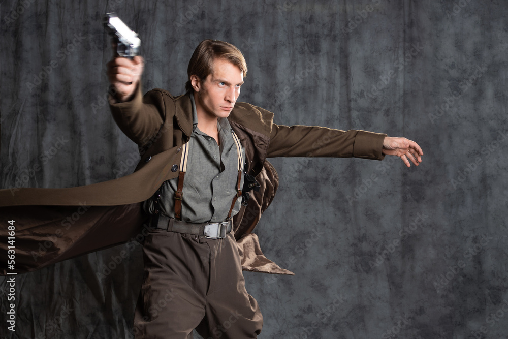 hero in a military style with a gun in his hands, a young man in a long ...
