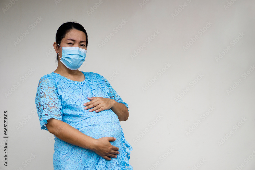 Pregnant Asian woman wears hygienic face mask, holds her big belly, 9 ...