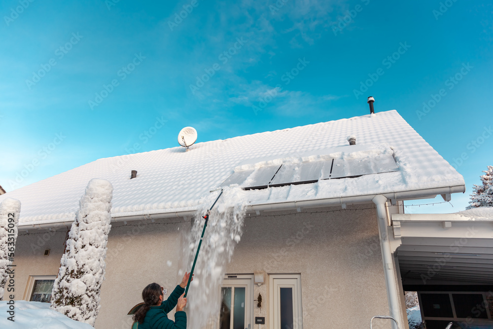 man cleans the panel at rooftop from snow. removing snow off solar ...