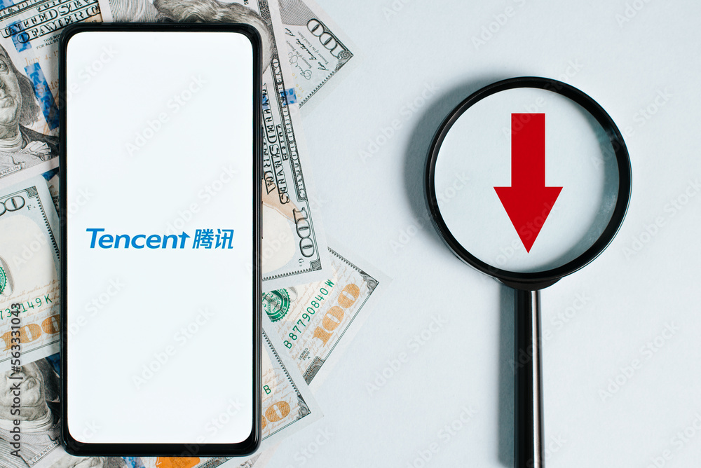 Tencent logo on phone screen, money, magnifying glass focused on red ...