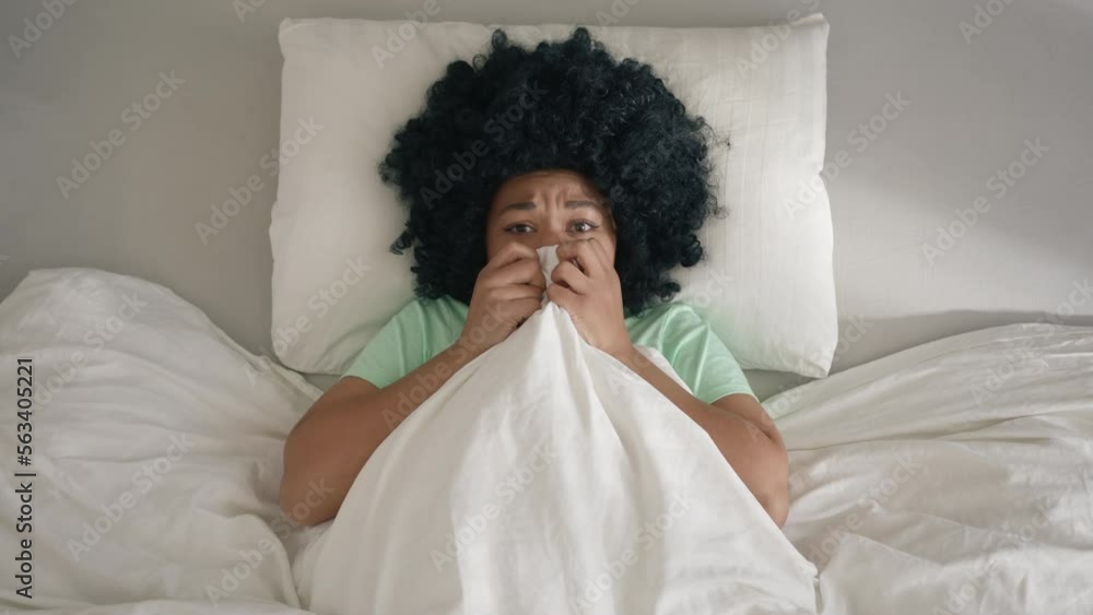 Video Stock Frightened African American woman scared of ghosts on bed ...
