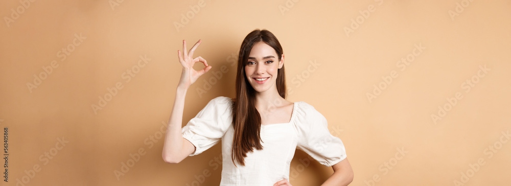 Very good. Smiling cute woman in white blouse showing okay sign in ...