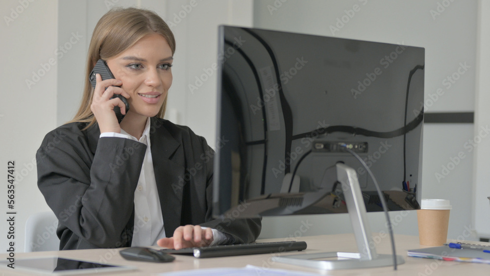 Young Businesswoman Talking on Phone while using Desktop Computer Stock ...