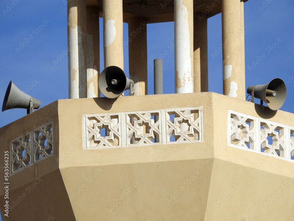 high minaret with loud speakers of a mosque against a lovely blue sky ...
