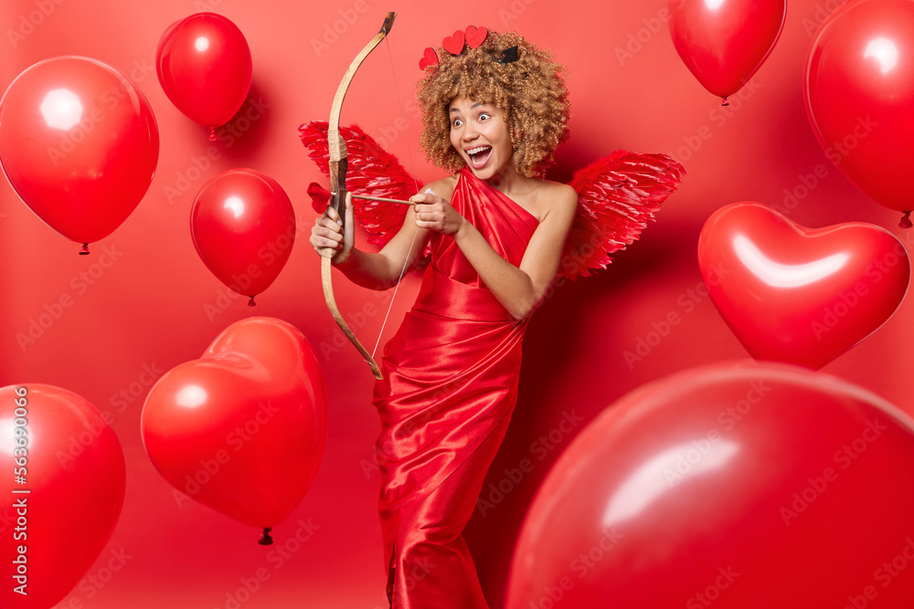 Happy positive female model pretends being cupid shoots with arrow at ...