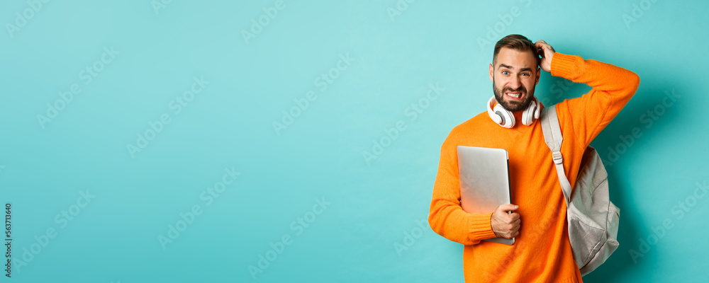 Confused male student looking puzzled and scratching head, holding ...