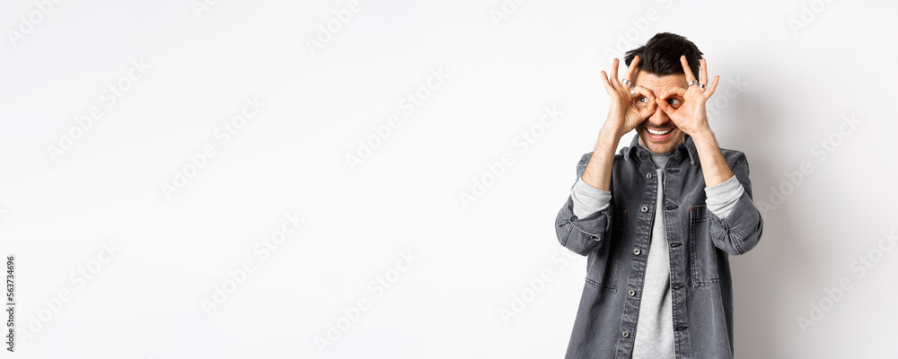 Smiling guy looking left at logo through hand binoculars, see good dea ...