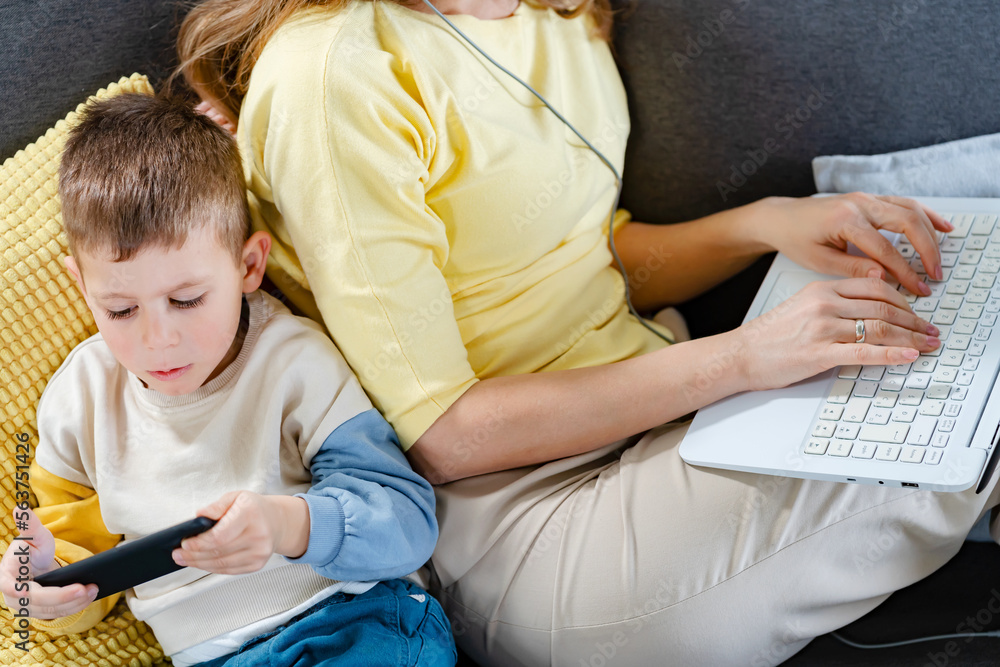 Little boy using smartphone to amuse himself while his mother is ...