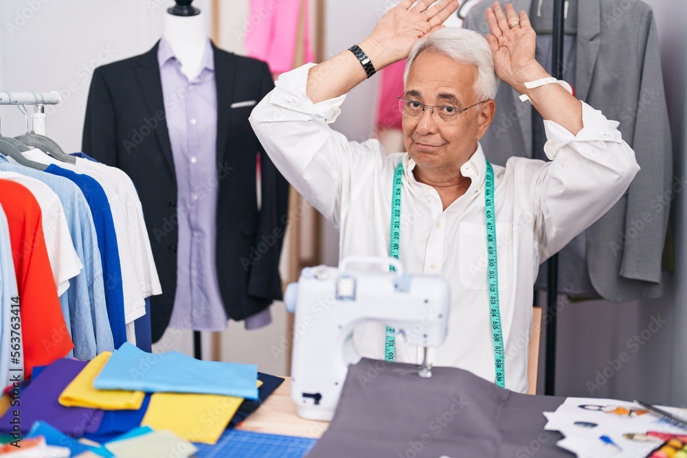 Middle age man with grey hair dressmaker using sewing machine doing ...
