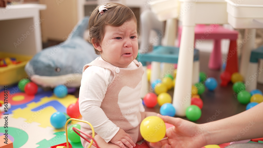 Poster Adorable toddler sitting on floor looking ball crying at ...