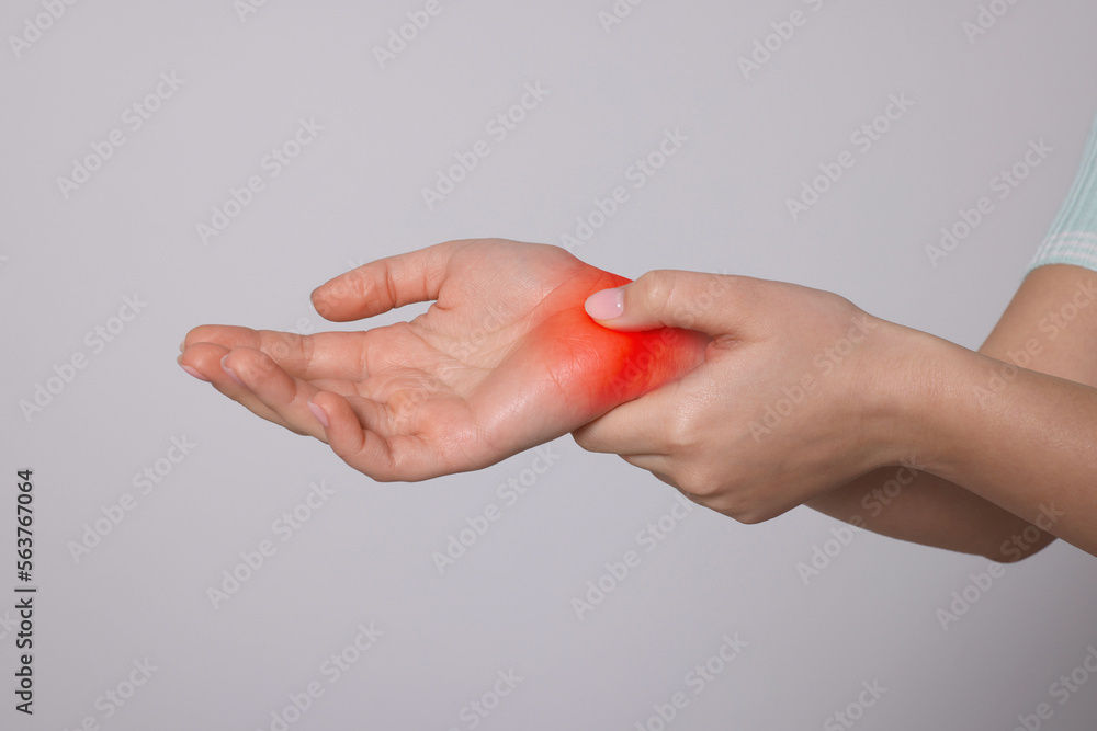 Arthritis symptoms. Young woman suffering from pain in wrist on light ...