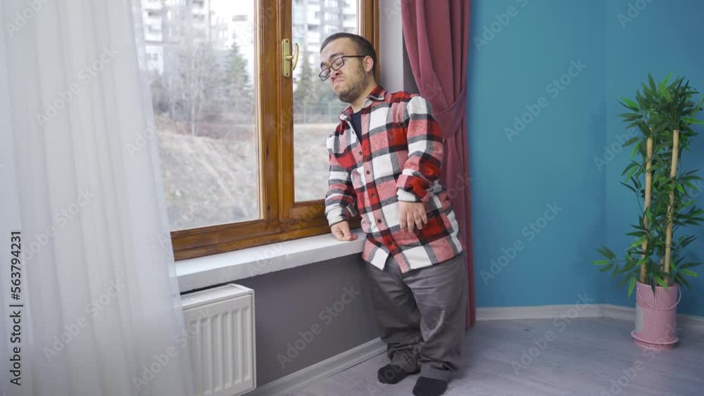 Crying dwarf man looking out the window at his house. The dwarf man is ...