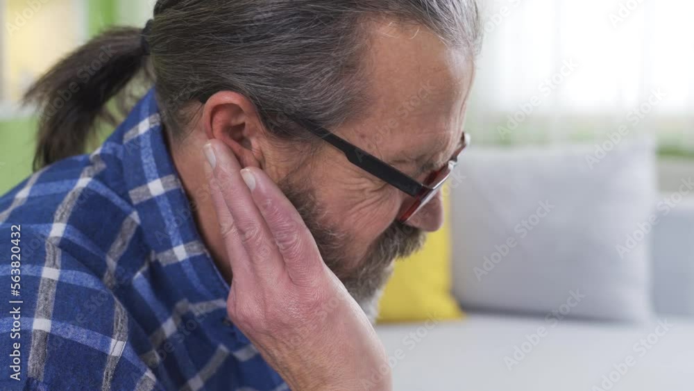 Close-up shot of old man with sore ears at home. Disease. Old man with ...