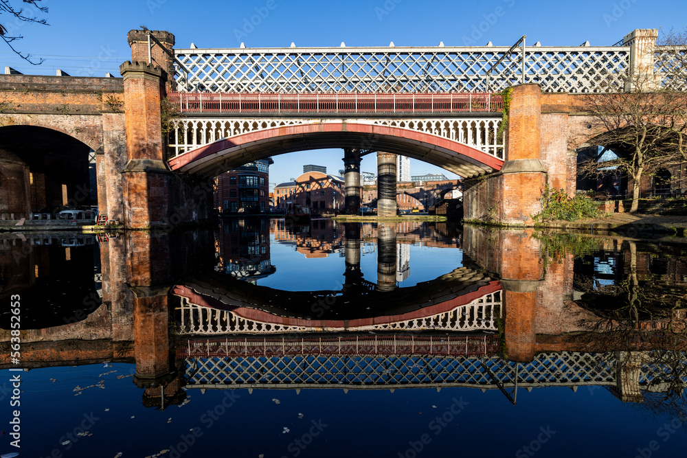 UK, England, Manchester, Arch bridge reflecting on surface of canal ...