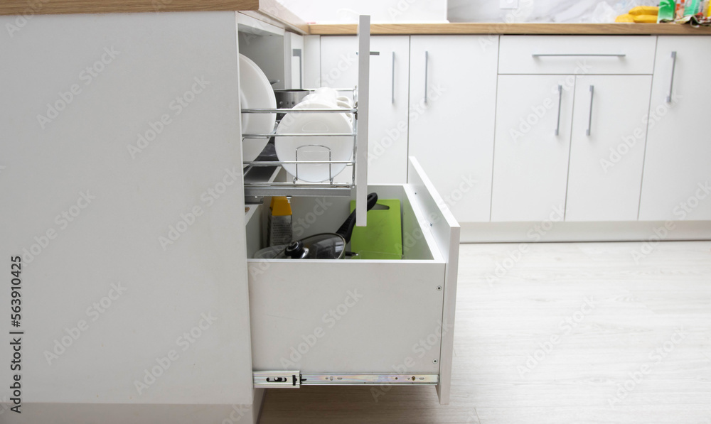 Modern white kitchen with sliding shelves for dishes and pans. A set of ...