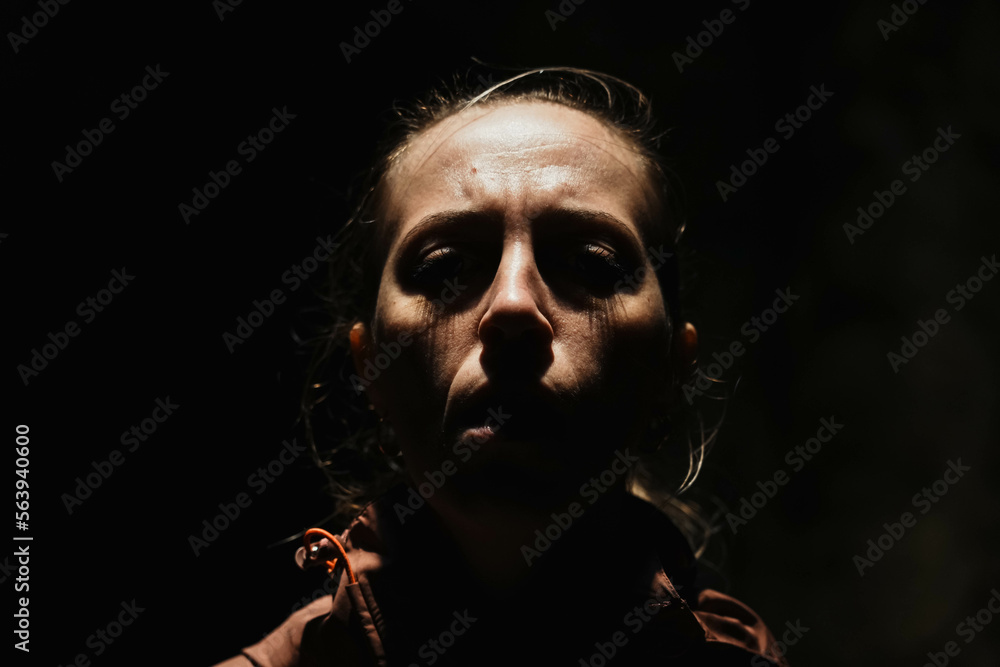 Portrait of slim blonde woman with light from above. Shadowed eyes and ...