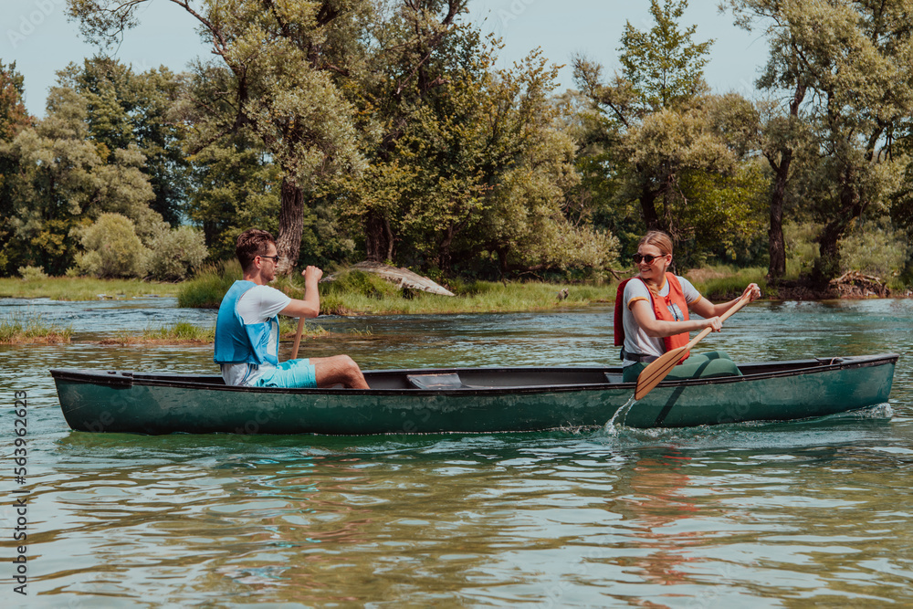 Couple adventurous explorer friends are canoeing in a wild river ...