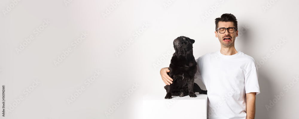 Image of sad crying man hugging his cute black pug, dog looking curious ...