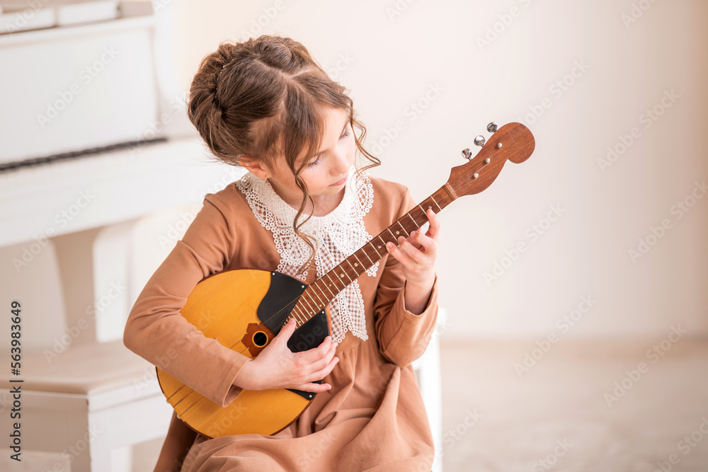 A teenage girl a young musician plays a stringed musical instrument ...