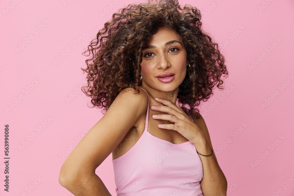 Woman with curly afro hair model poses on a pink background in a pink T ...