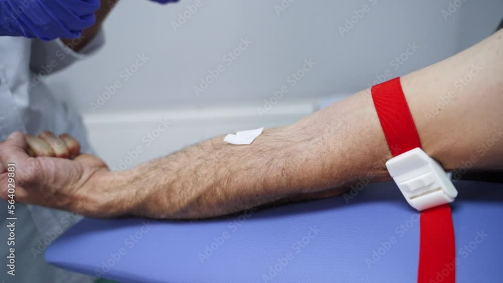 Male bare hand prepared for a blood test. Nurse in latex gloves inputs ...