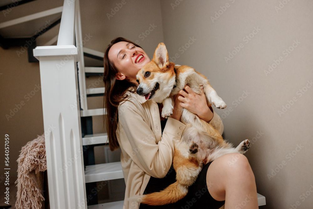 Attractive girl hug and play with corgi dog at home. Welsh Corgi ...