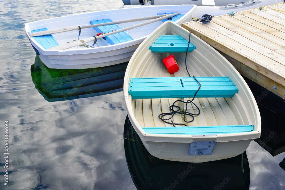 Two small wide white fiberglass dixie dingy boats moored at a wooden ...