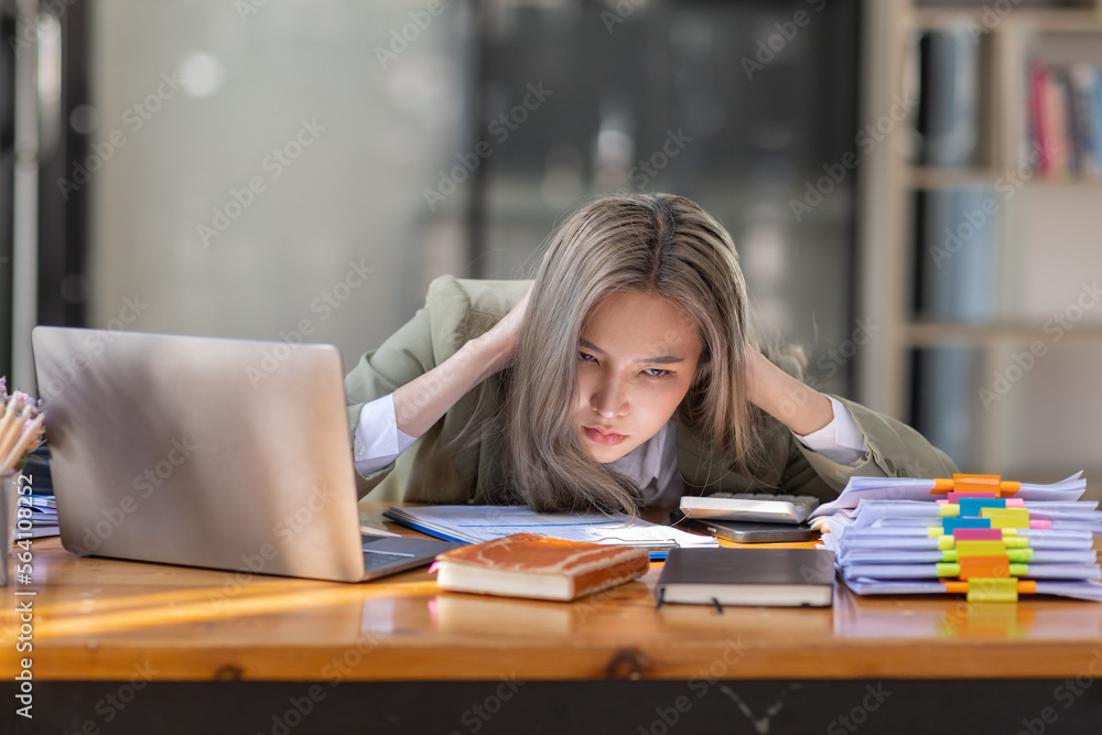 Foto de Bored Young business Asian woman sitting at her workplace at ...