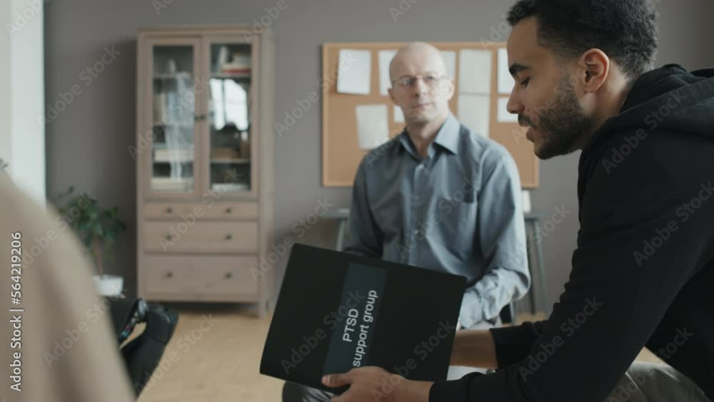 Selective focus of young Black man attending PTSD support group telling ...