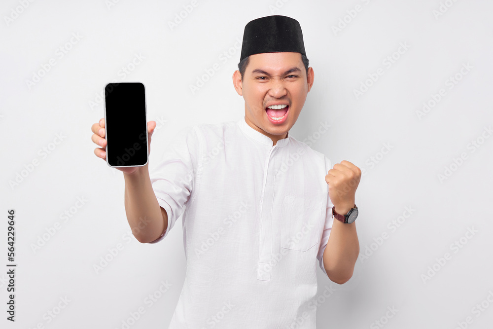 Excited young Asian Muslim man showing mobile phone screen and ...