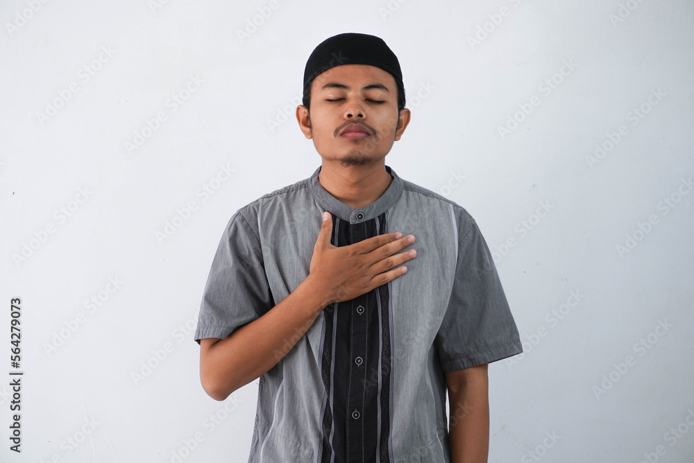 young Asian muslim man wearing grey muslim clothes with cap hands on ...