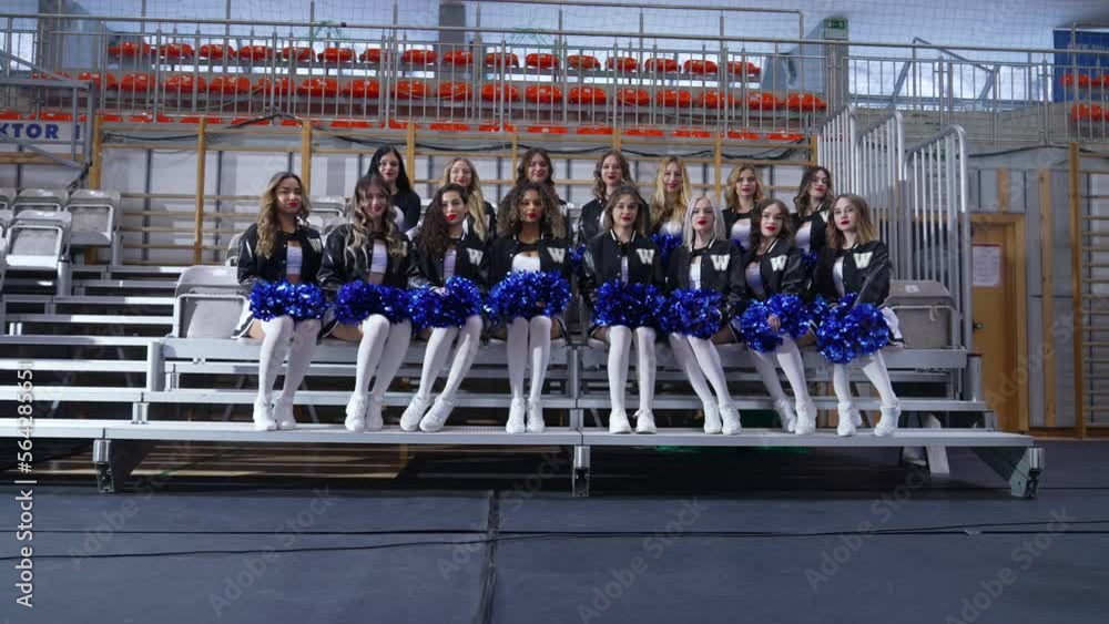 Cheerleaders in mini-skirts sitting on chairs posing for camera holding ...