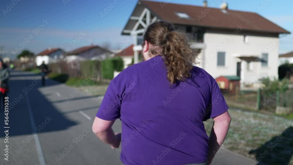 Back of an overweight man running outdoors getting back into shape. A ...