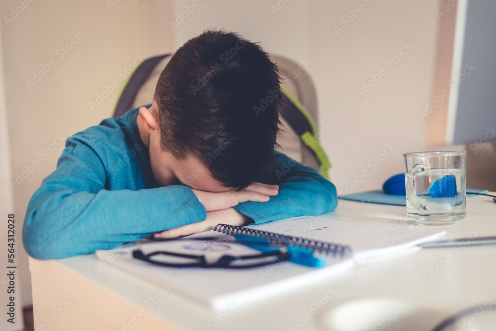 Frustrated young boy lays head done on schoolwork. Bored schoolboy from ...