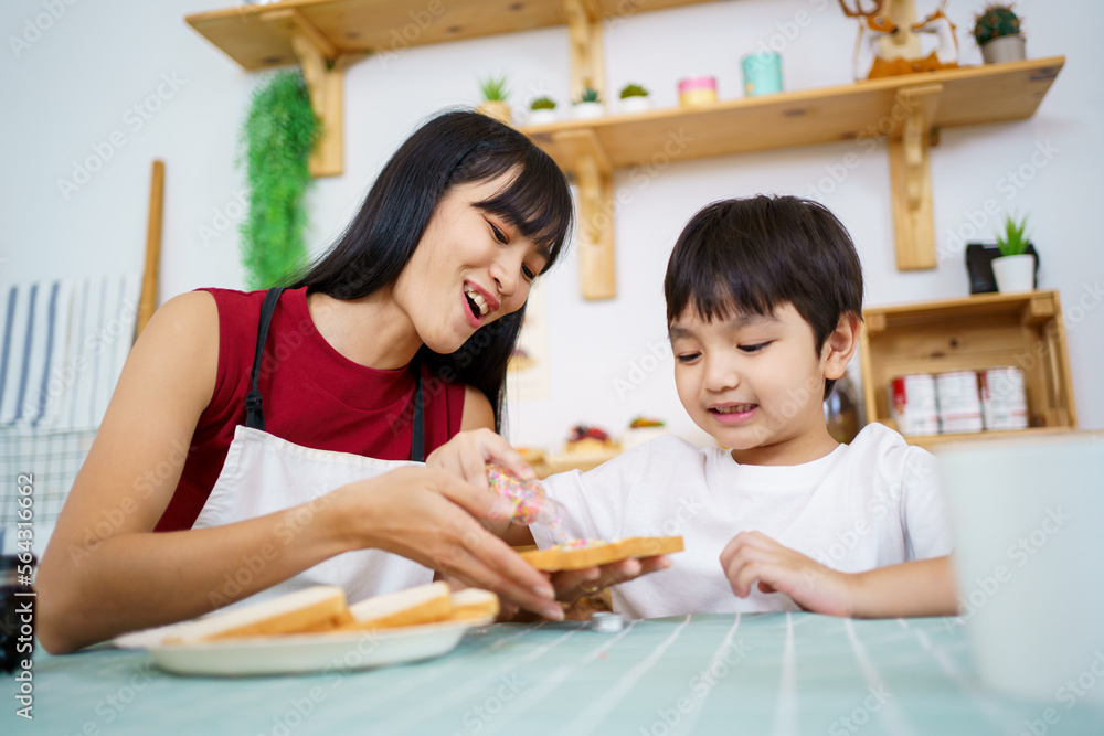 Happy little young boy and his mother making an easy breakfast together ...