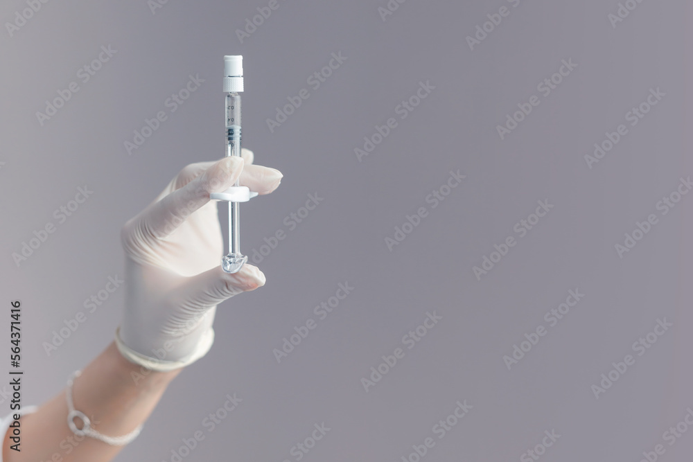Cosmetologist hand in medical glove holds syringe for injection with ...