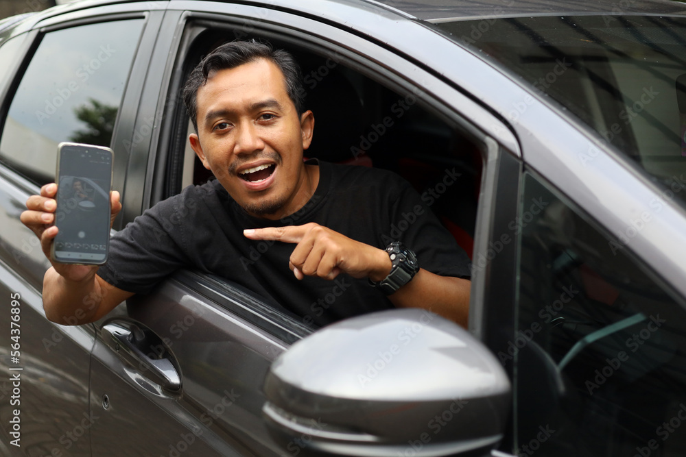 Happy asian driver pointing his cell phone screen in his car Stock ...