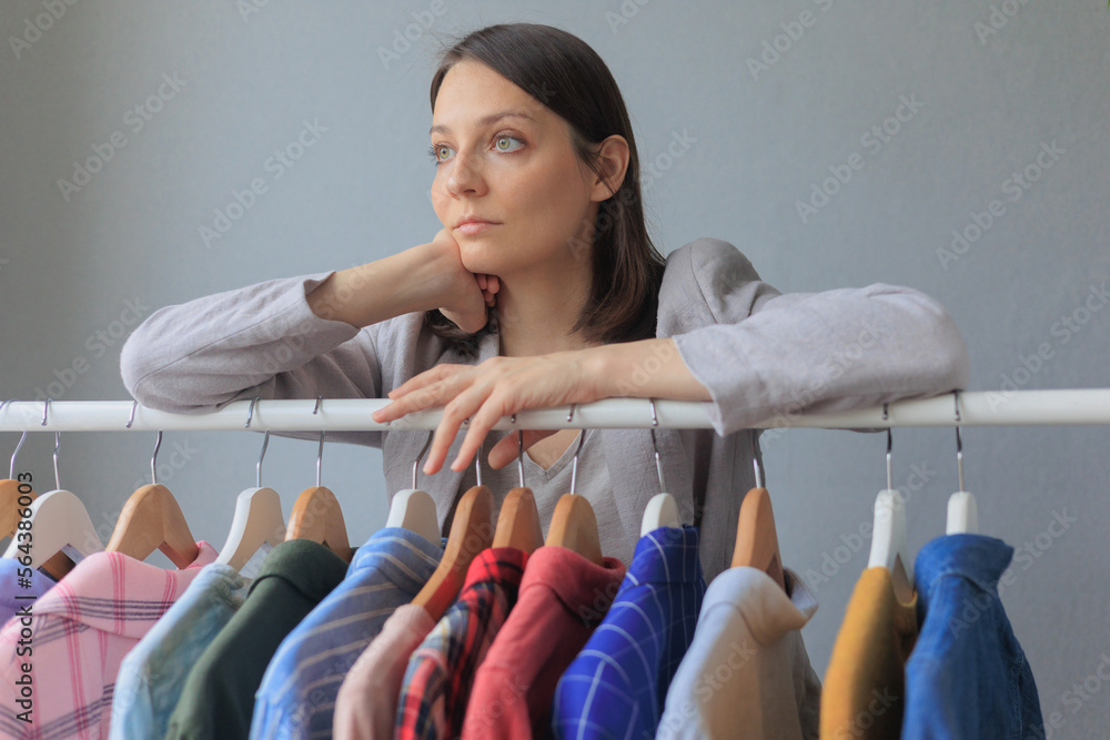 thoughtful woman does not know what to wear. selects clothes in ...