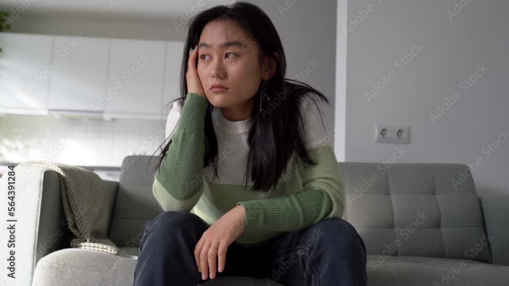 Vidéo Stock Anxiety disorder. Upset worried young Asian girl sitting on ...