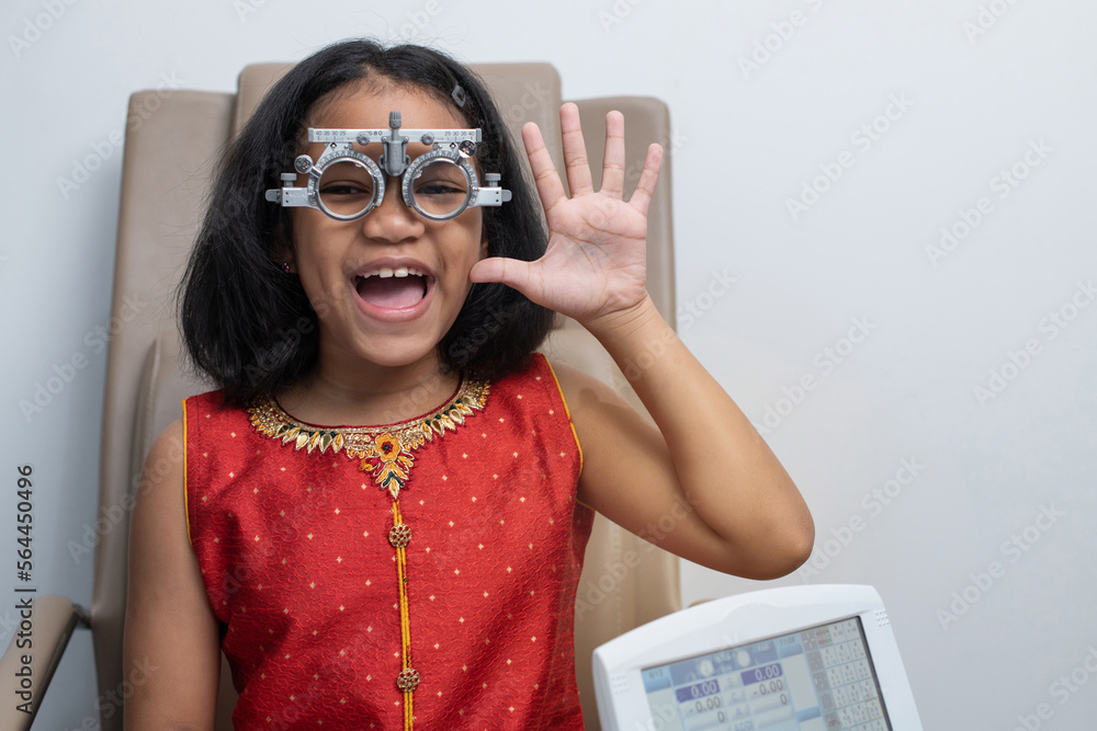Cheerful Indian girl laughing looking away during eye exam with trial ...