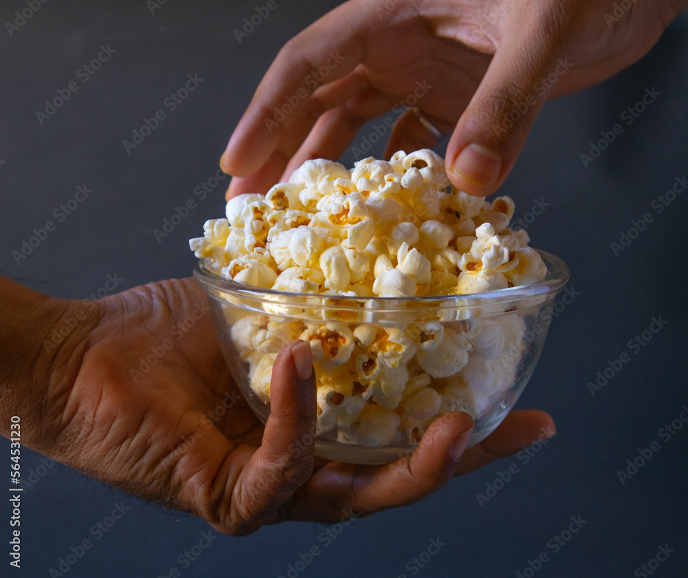 Picking up Golden Popcorn from a bowl in hand for an entertainment ...